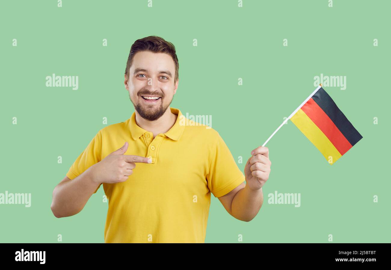 Happy German man isolated on green background holding flag of his ...
