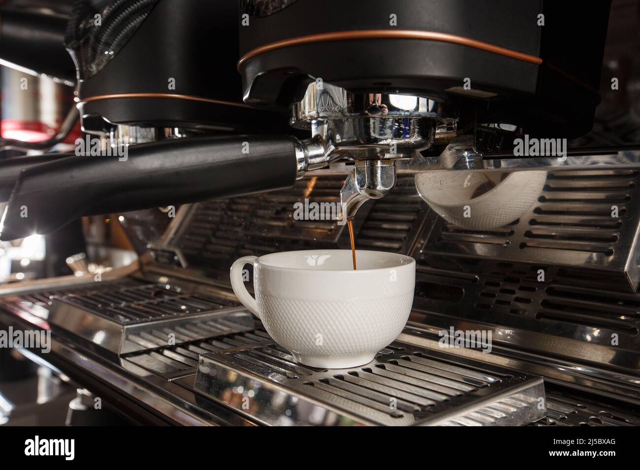 Pouring coffee stream from professional machine in cup. Barista making ...