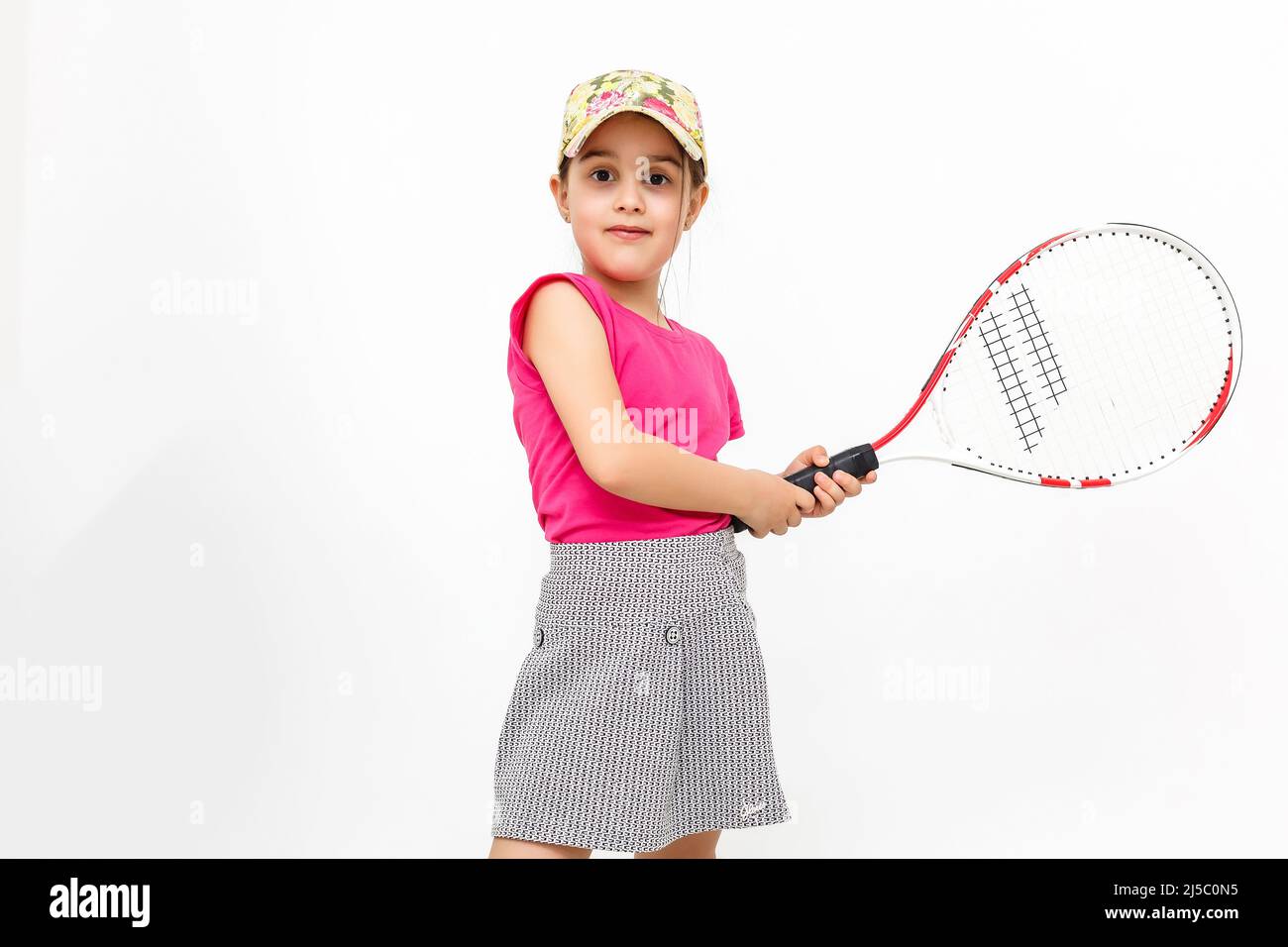 Cute little girl with tennis racket in her hands on white background ...