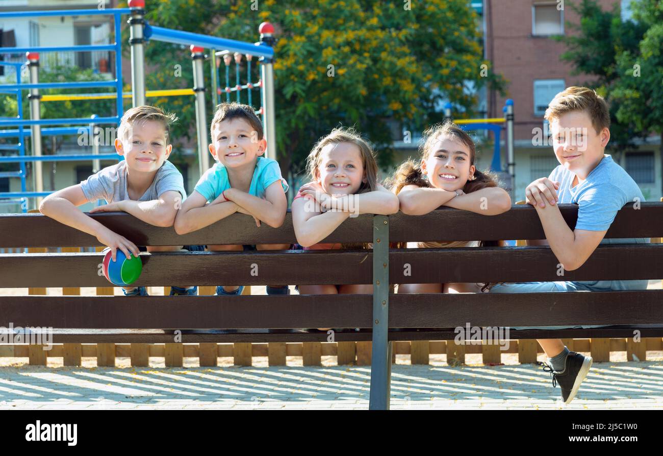 Five children sitting on a bench at the playground Stock Photo - Alamy
