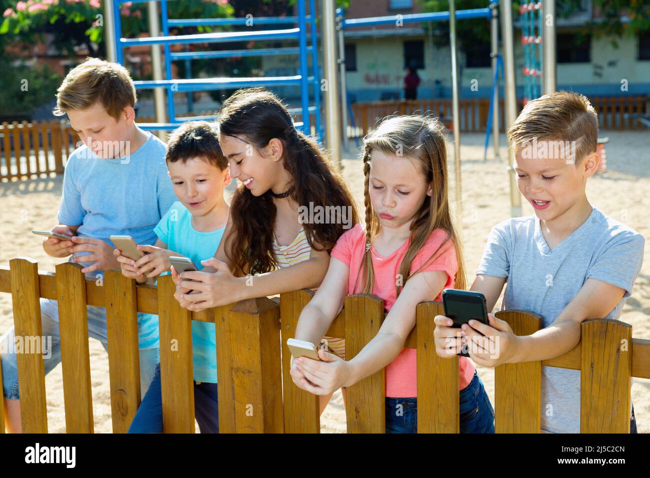 Five children sitting and playing in smartphone at the playground Stock ...