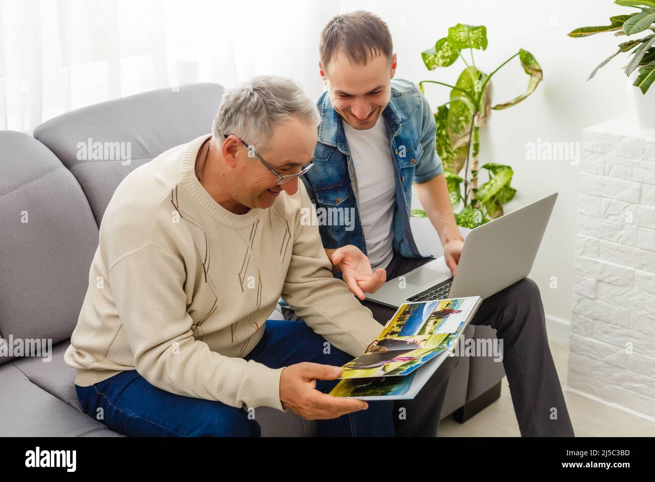 Parents and son together look at photos in the photobook at home Stock ...