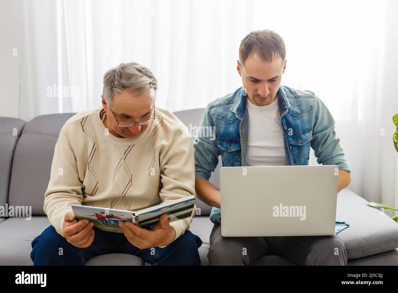 Parents and son together look at photos in the photobook at home Stock ...
