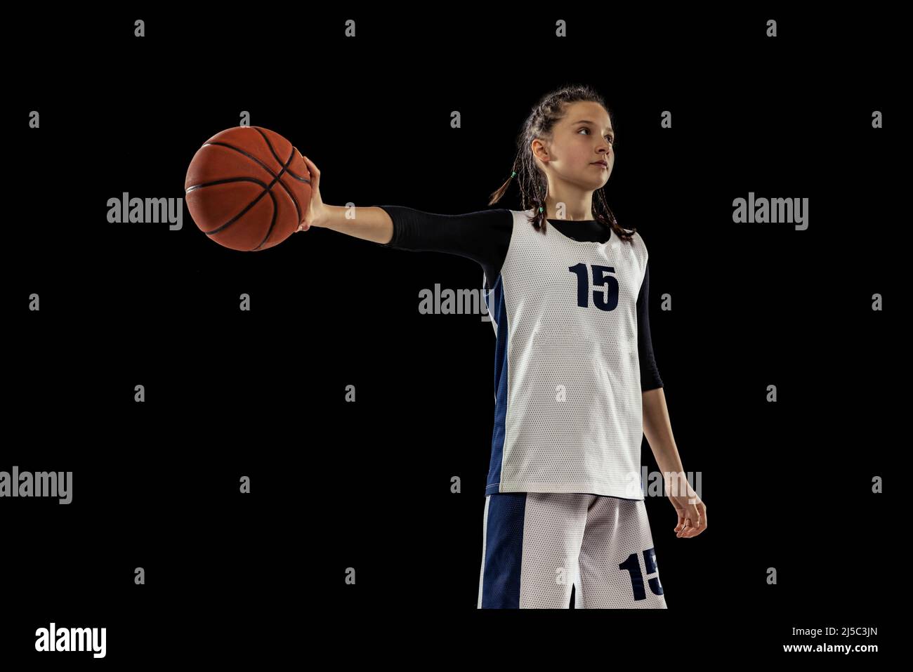 Portrait of young girl, basketball player holding ball with one hand ...