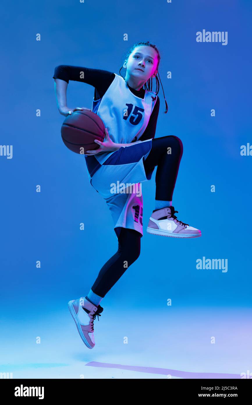 Studio shot of teen girl playing basketball, cathing ball in a jump ...