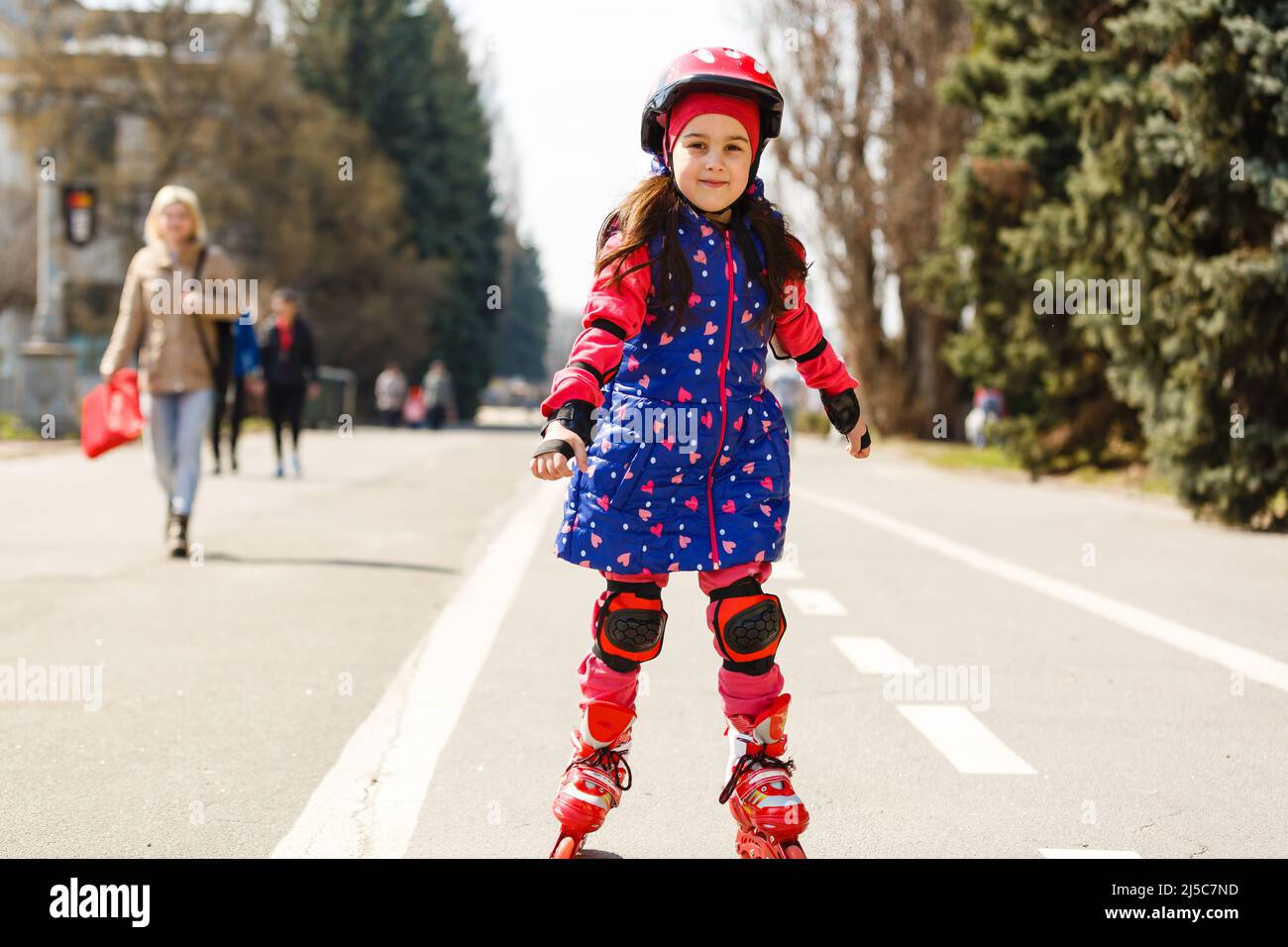 Little pretty girl on roller skates in helmet at a park Stock Photo - Alamy