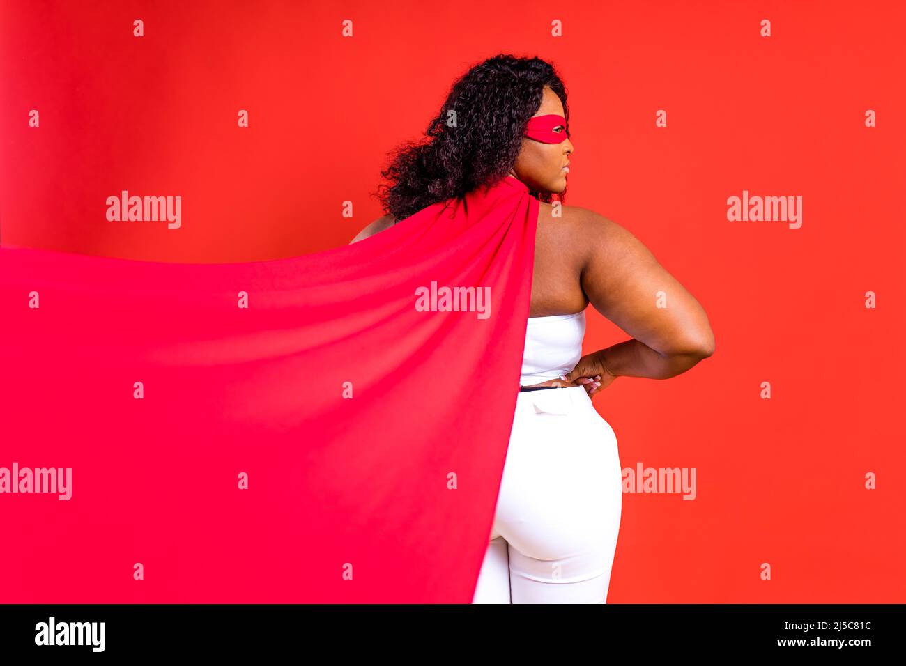 latin hispanic woman in red eye mask and long superhero cloak in studio ...