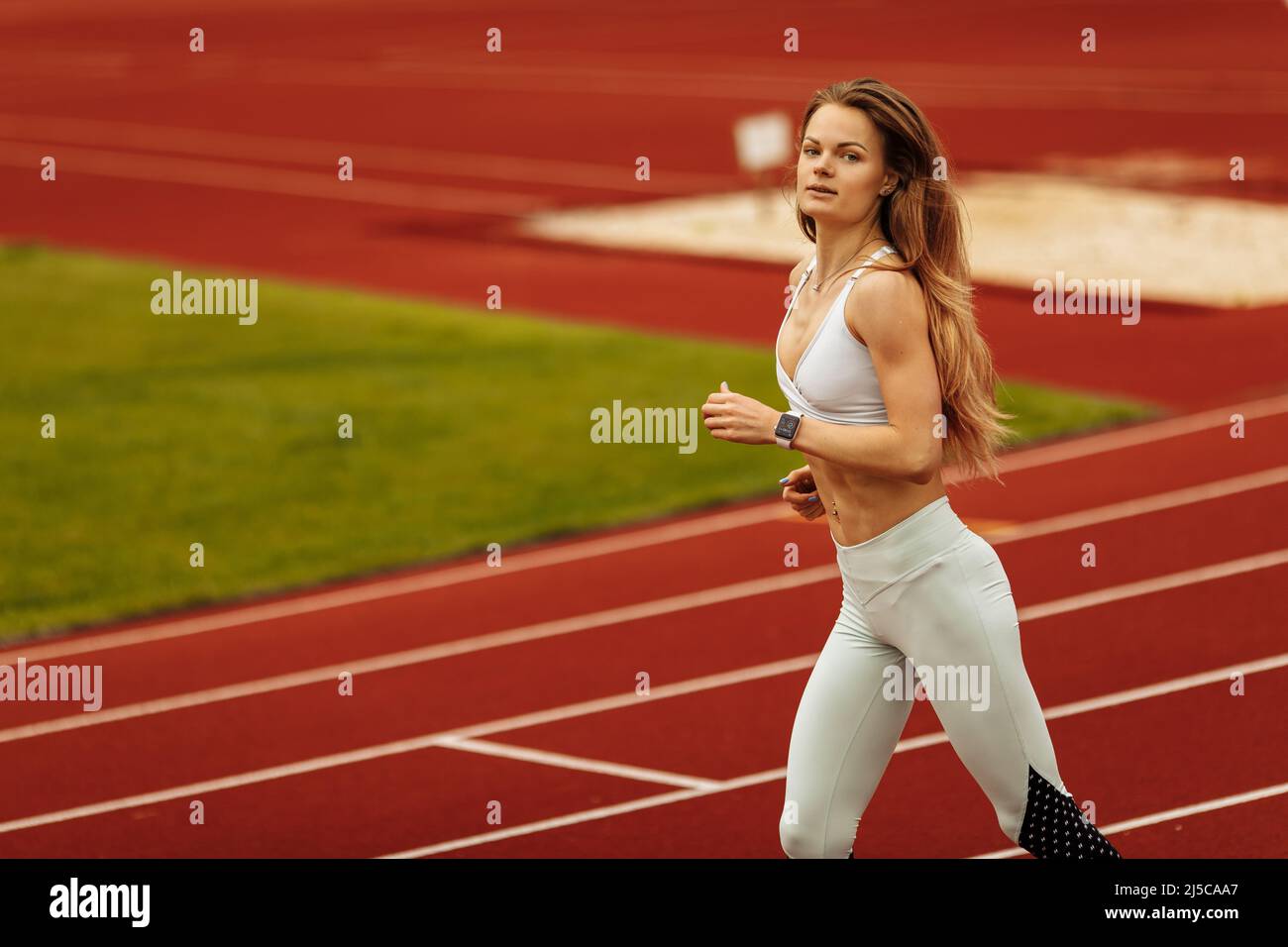 Athletic girl running at the stadium, working out, keep herself in ...