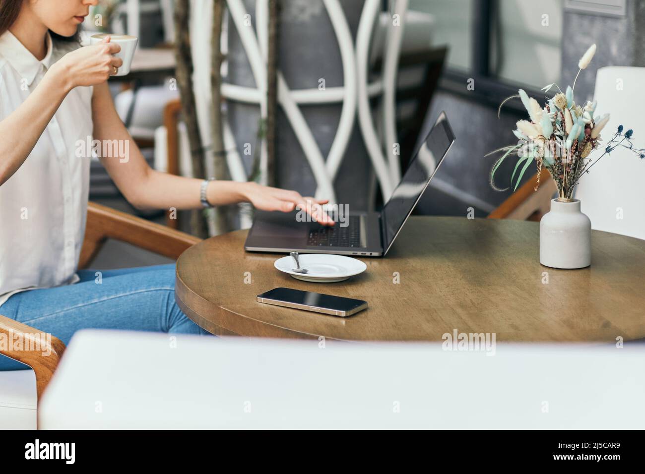young woman is drinking coffee and looking through e-mail in a cozy ...