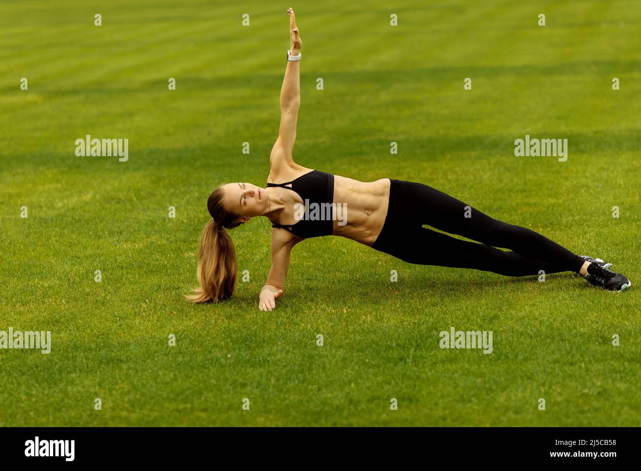 Strong athletic woman working out at the stadium, do a side plank ...