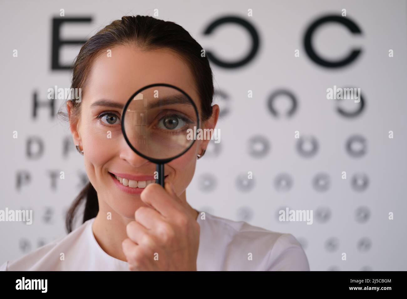 Doctor ophthalmologist looks through magnifying glass in ...