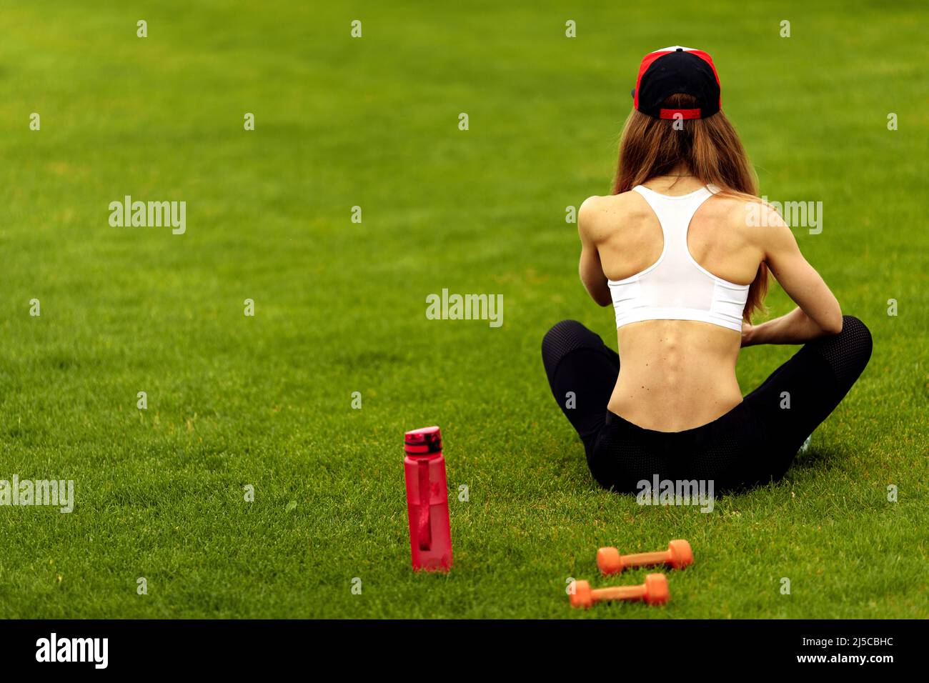 Athletic woman rest after workout, sporty girl sitting at the grass ...
