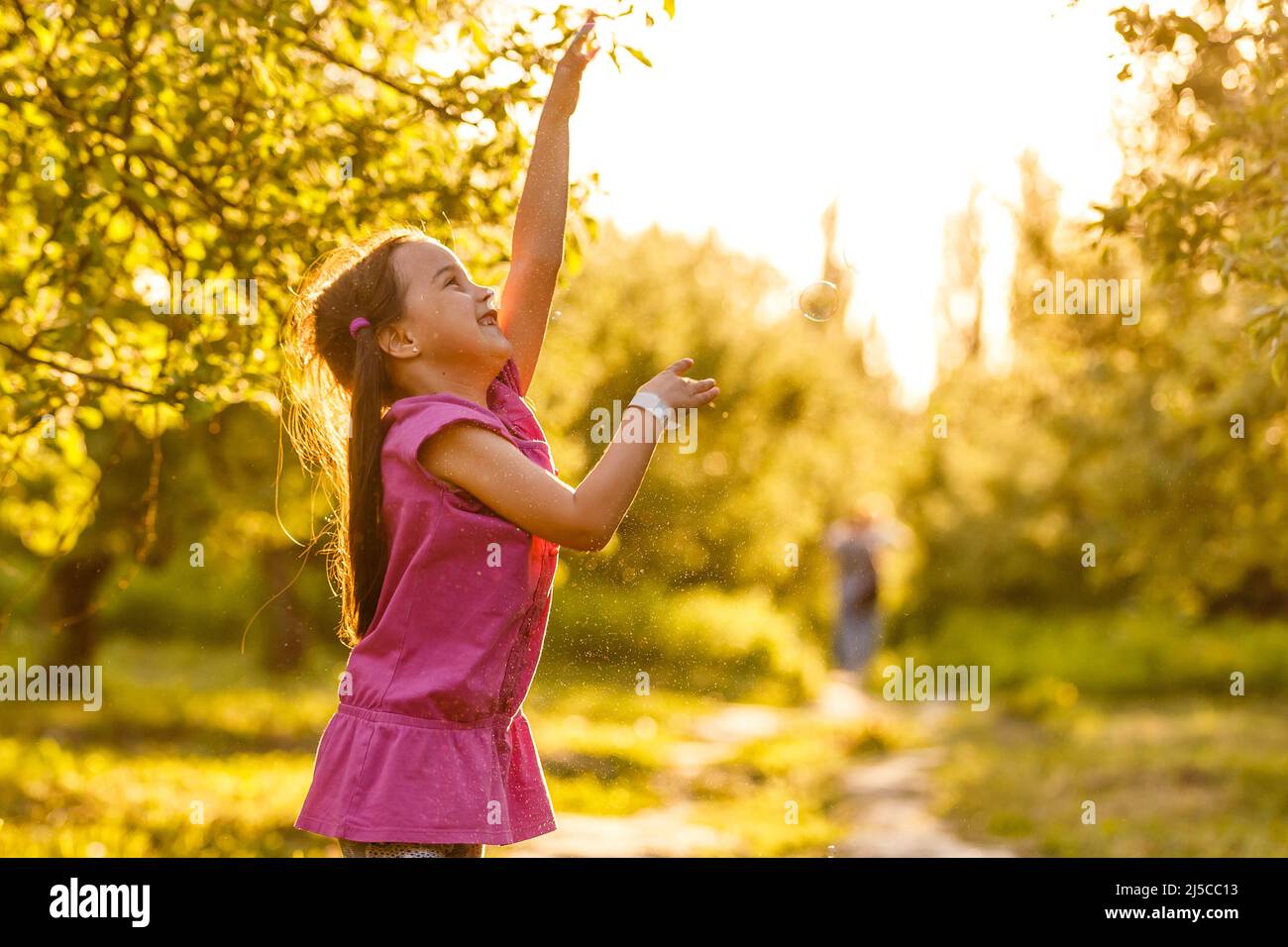 Sweet child child trying to catch soap bubble Stock Photo - Alamy