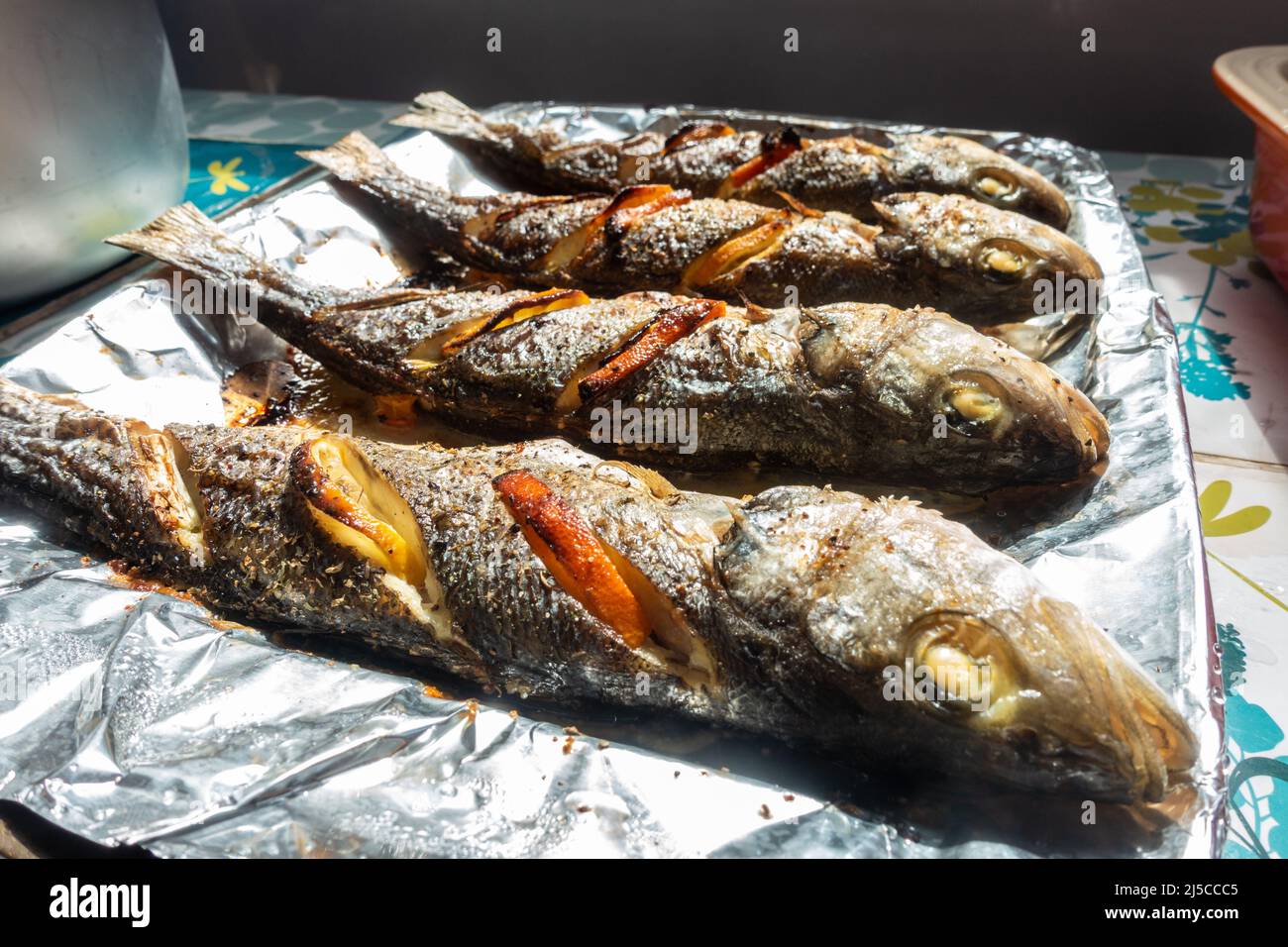 Four fish baked on a tray covered with aluminium foil Stock Photo - Alamy
