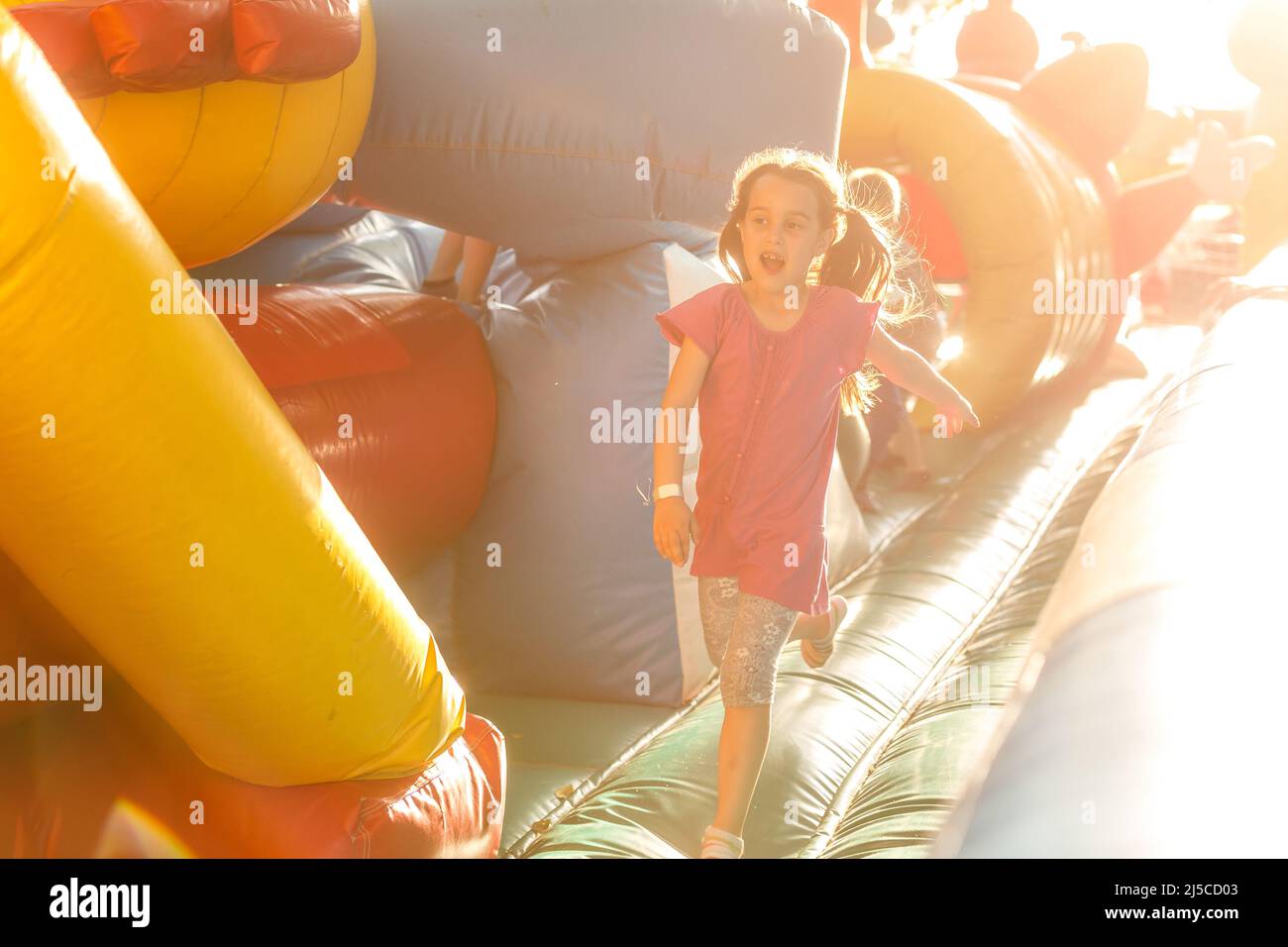 Happy little girl having lots of fun on a jumping castle during sliding ...