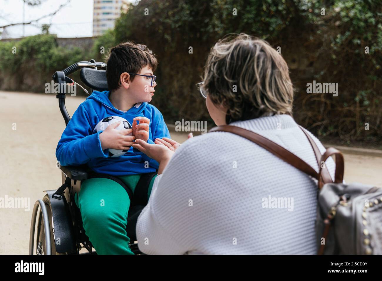 A child with a disability in a wheelchair holding a soccer ball playing ...