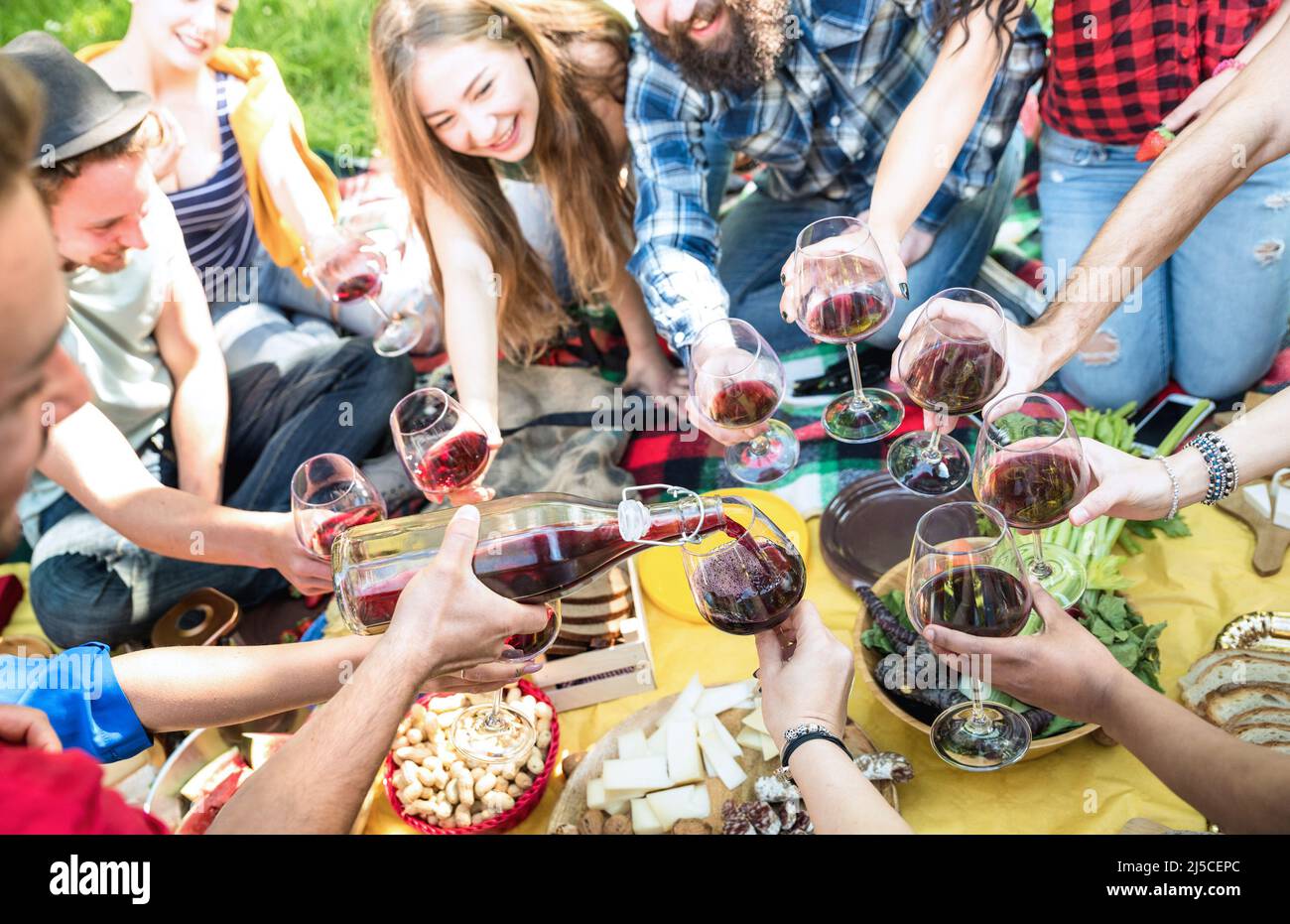 Side View Of Friends Serving And Toasting Red Wine Glasses