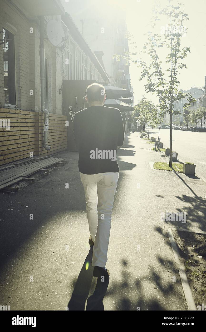 A man walking on the sidewalk in the backlight | A man on the boardwalk ...