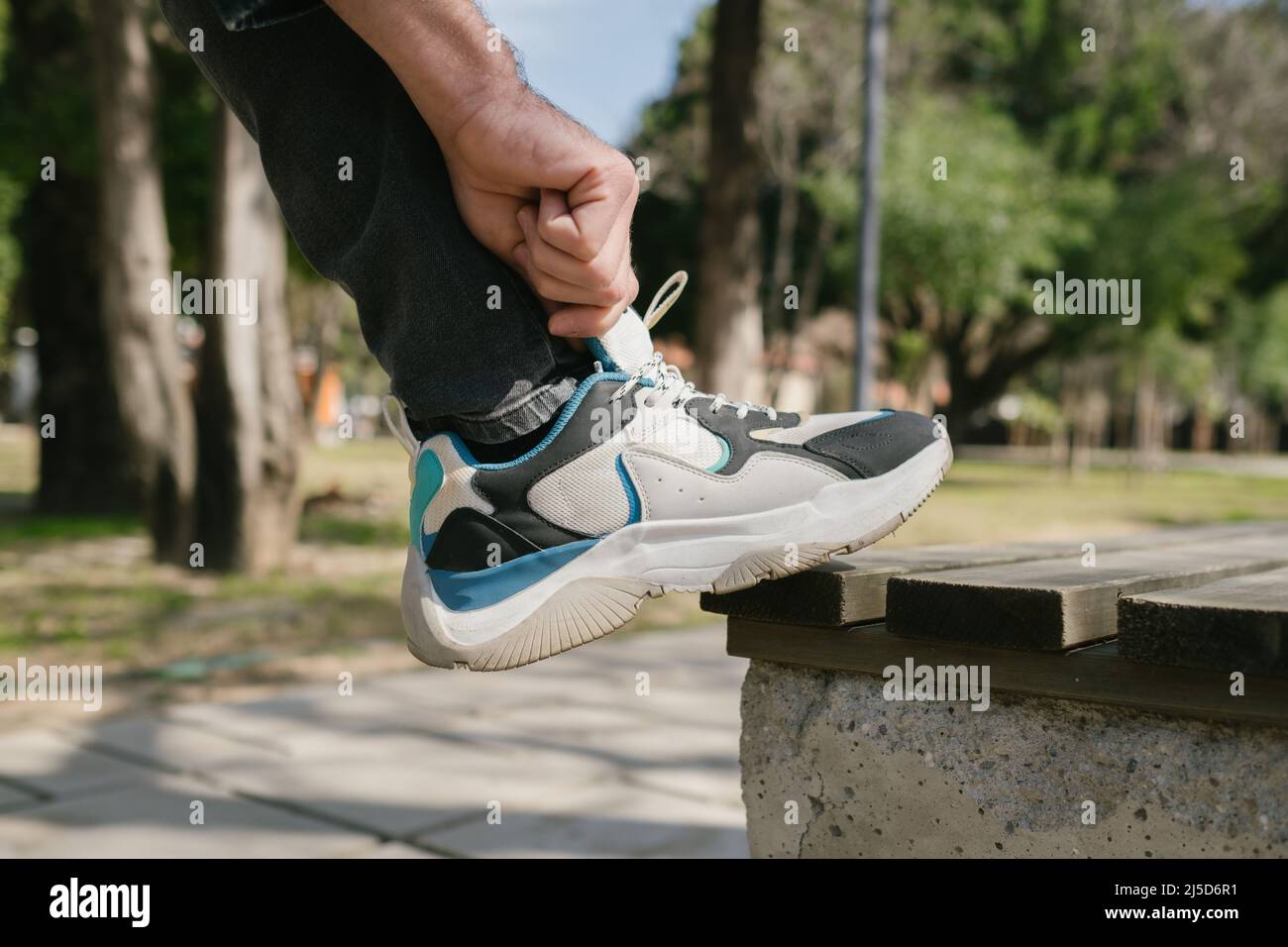 Close up walking man stand step on the footpath trying shoelace shoes ...