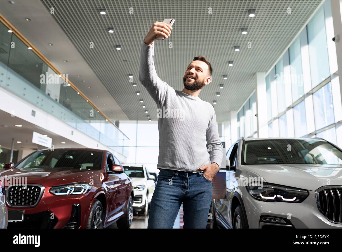 a middle-aged man in an off-road car dealership takes a selfie between ...