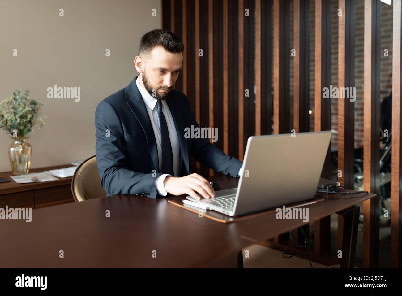 male insurance agent in a suit in the office working on a laptop Stock ...