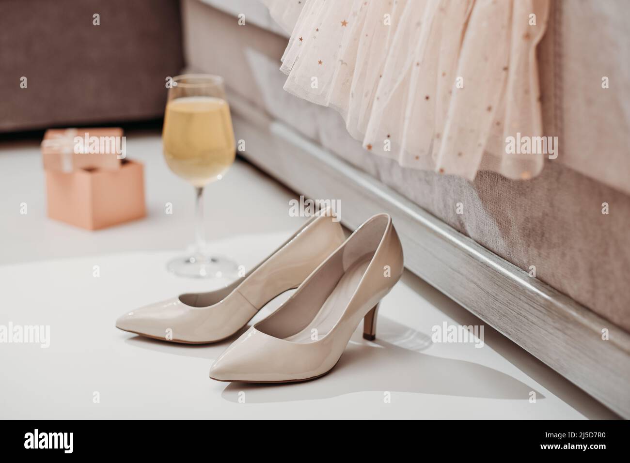 elegant beige lady shoes, vine glass and gift box next to a couch ...