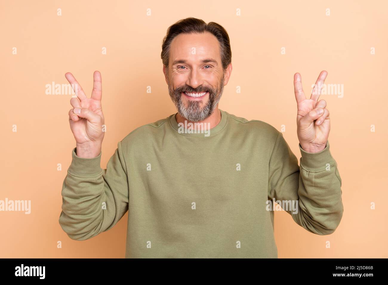 Portrait of attractive cheerful man showing double v-sign good mood ...