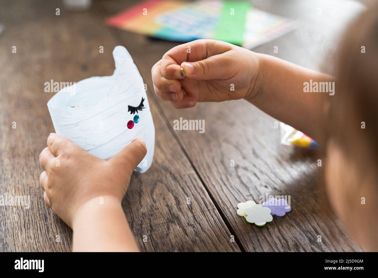 Caucasian preschool girl doing crafts with plastic bottle and paints ...