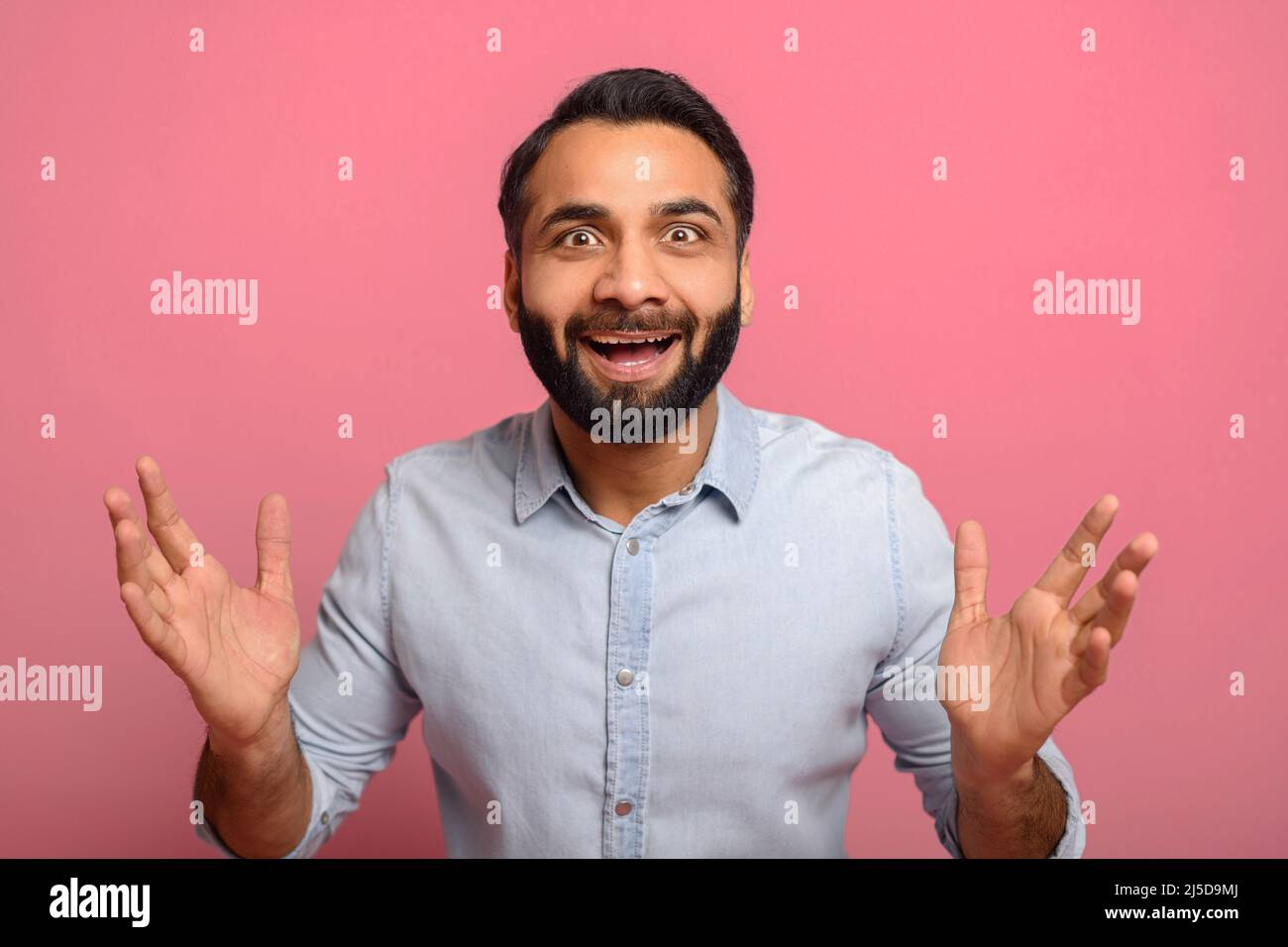 Surprised overjoyed Indian guy staring at the camera isolated on pink ...