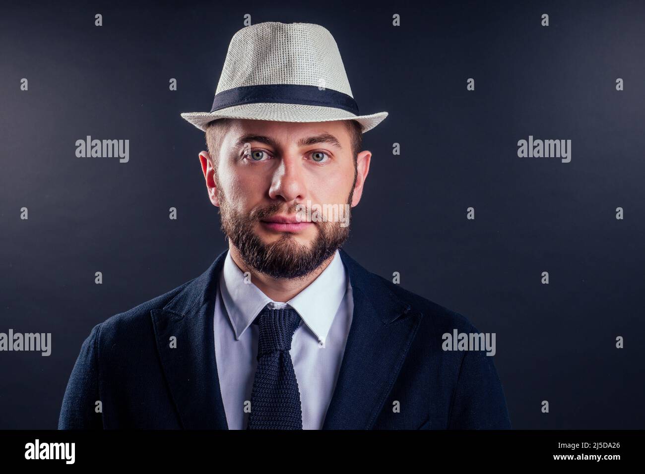 Portrait of handsome young businessman wear hat over black background ...