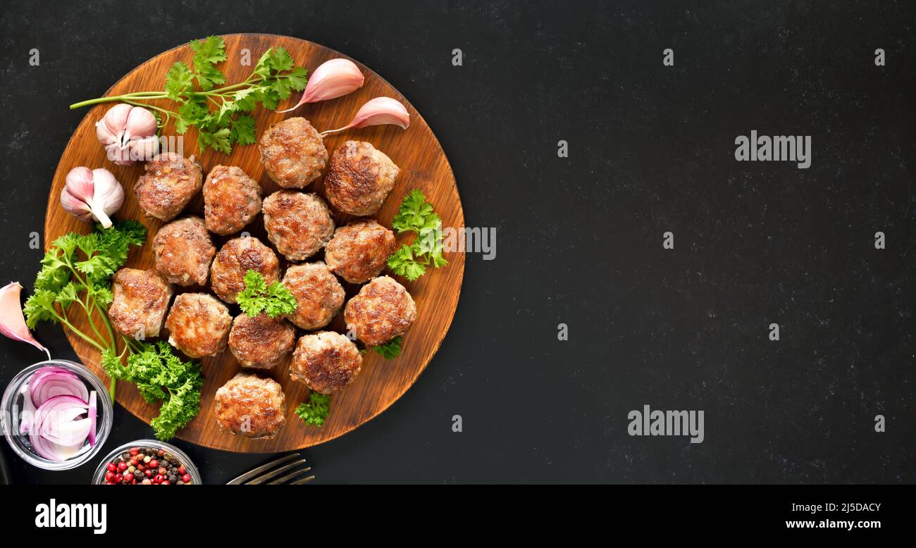 Fried meatballs on cutting board over dark stone background with copy ...