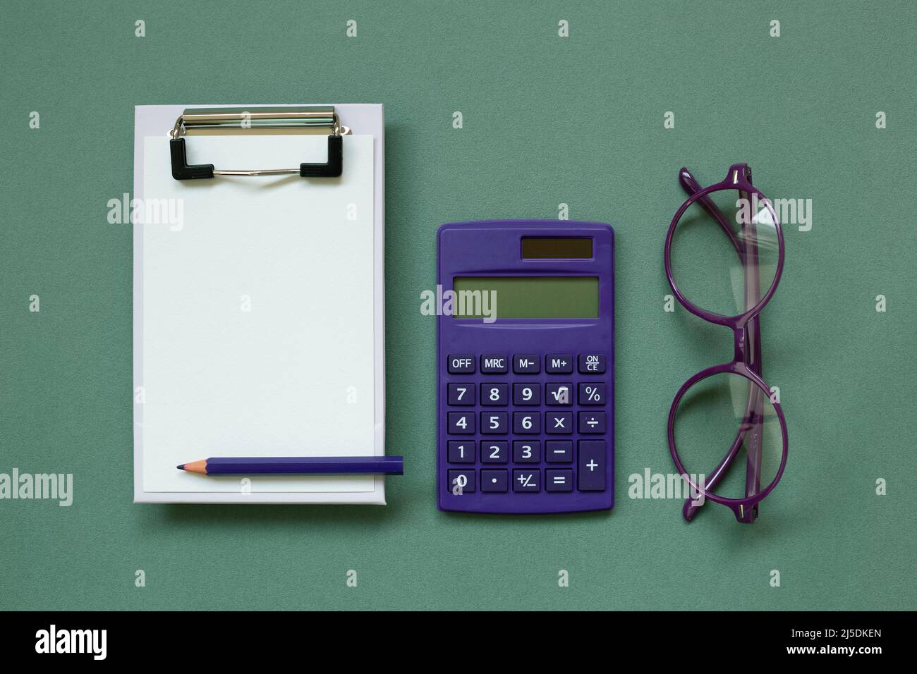 Clipboard and paper sheet, calculator, glasses on green background. top ...