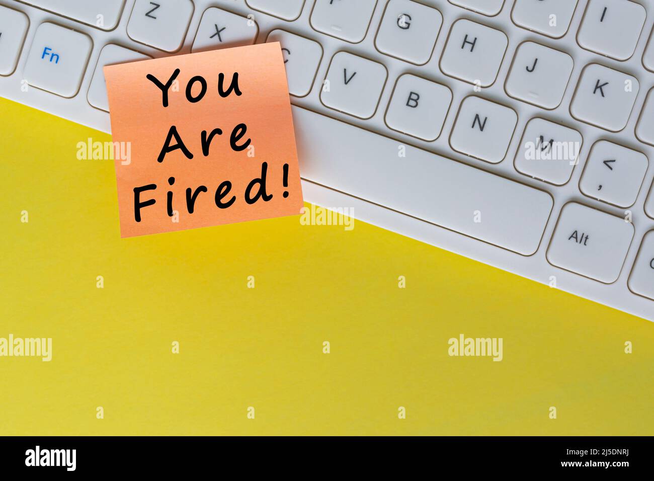 You're Fired text on orange sticky note on top of white keyboard. Human ...
