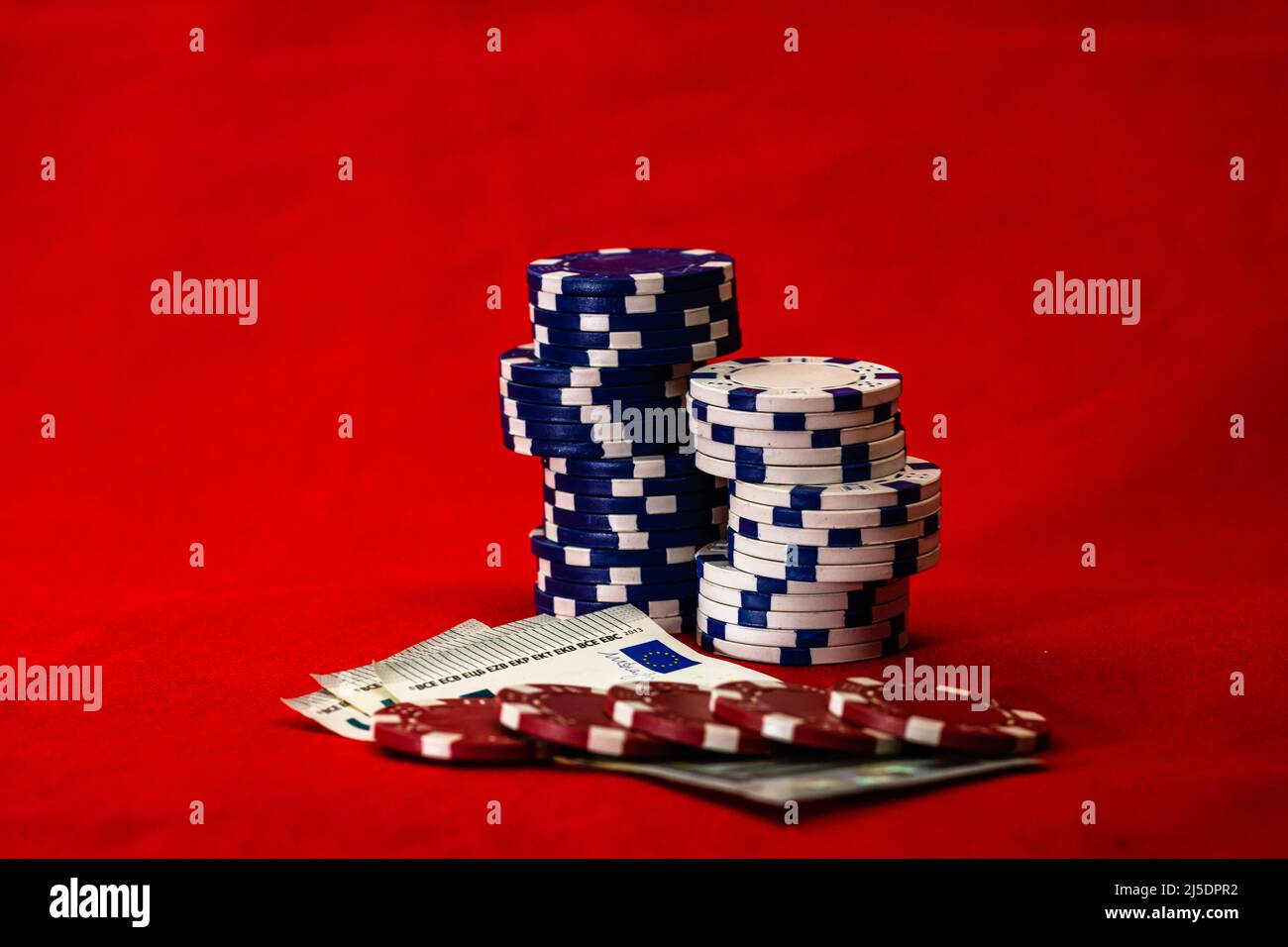 Stacks of poker chips with money on red background, EURO currency Stock ...