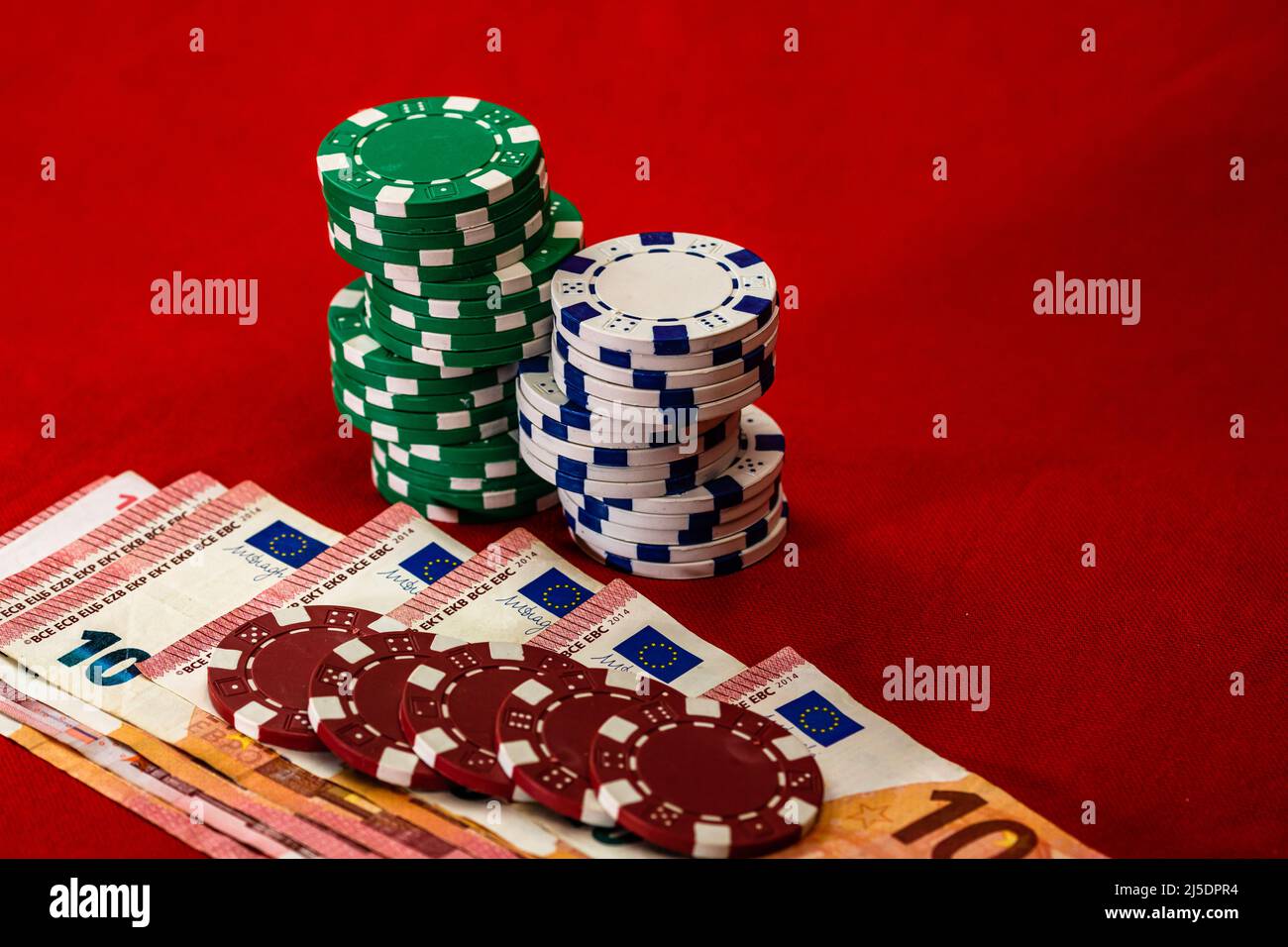 Stacks of poker chips with money on red background, EURO currency Stock ...