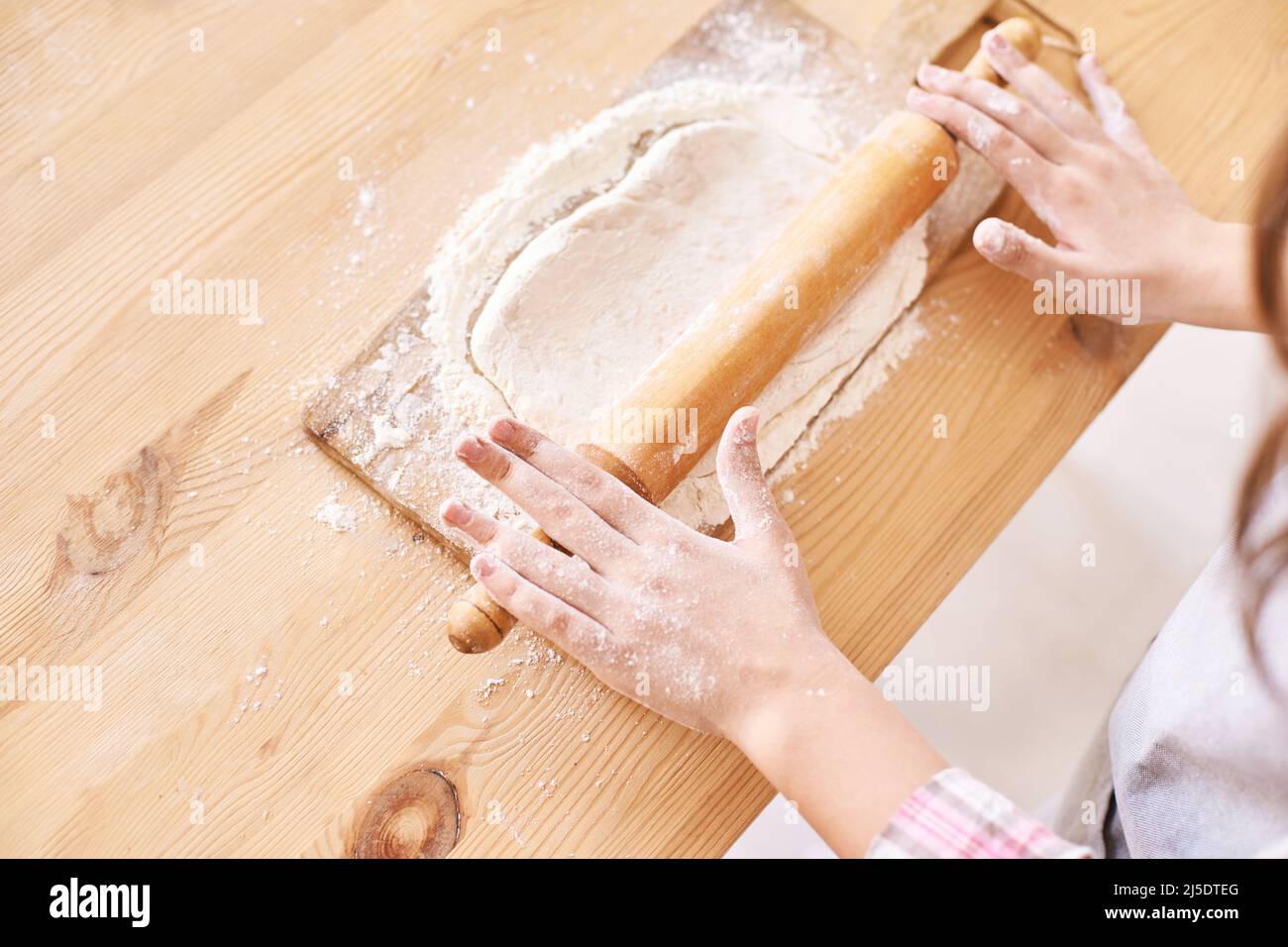 Young girl cooking at kitchen. Curly pretty child portrait. Chef student. Attractive brunette ...