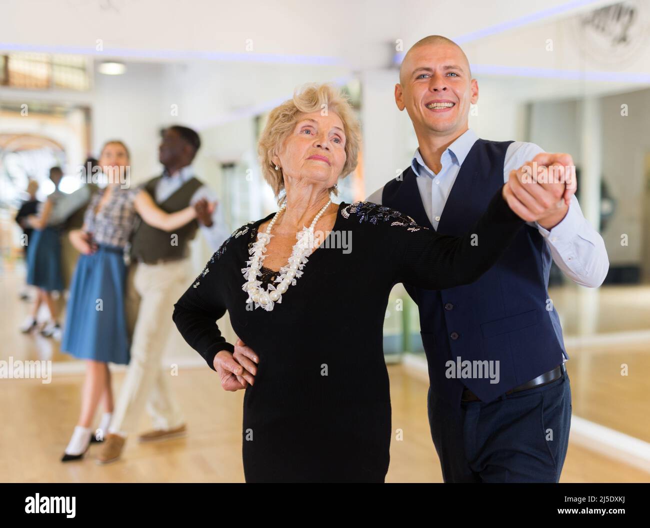 Elderly woman learning ballroom dancing movements in pair Stock Photo ...