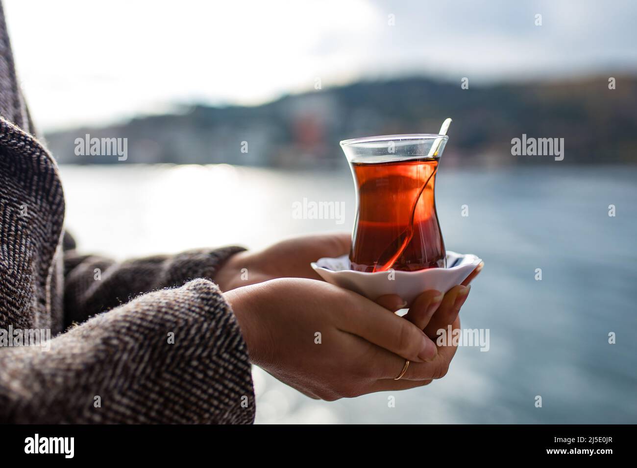 woman drinking Turkish tea in the front, bosphorus bay in the ...