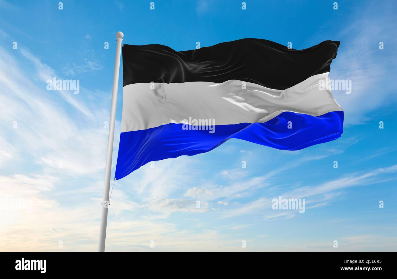 official flag of Moresnet, Belgium at cloudy sky background on sunset ...