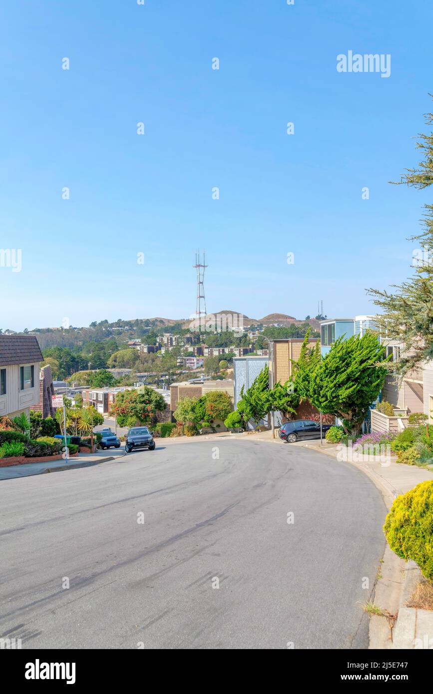 Asphalt road with parked vehicles on a sloped residential area in San ...
