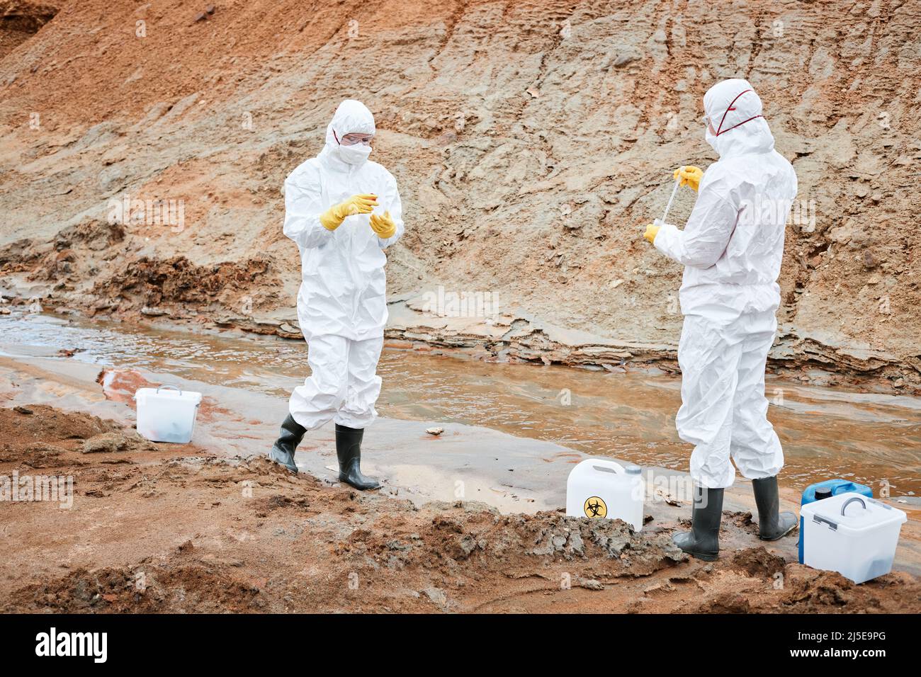 Environmental scientists in masks, gloves and protective suits working ...