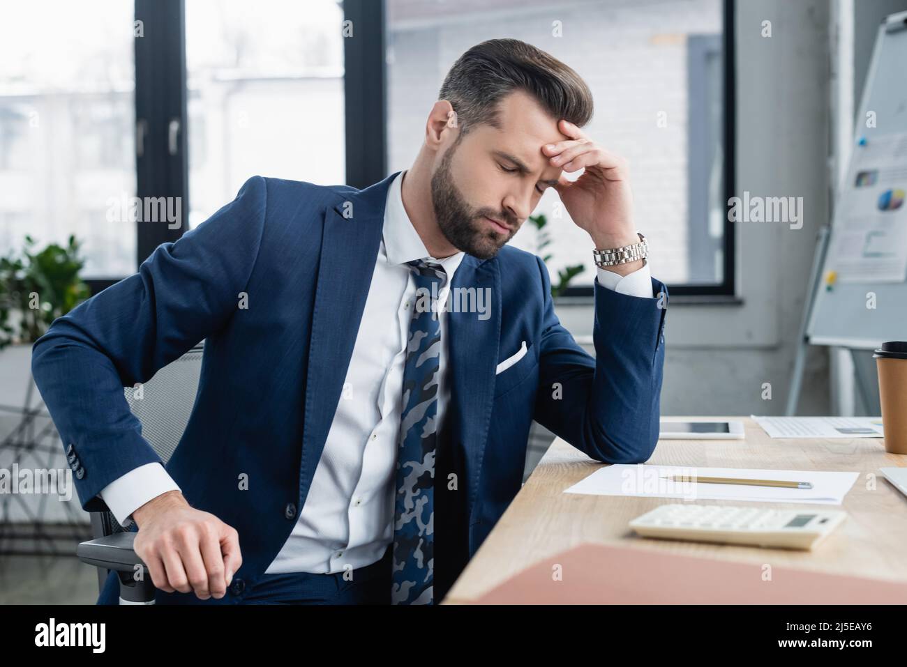 exhausted accountant sitting with closed eyes near blurred calculator ...