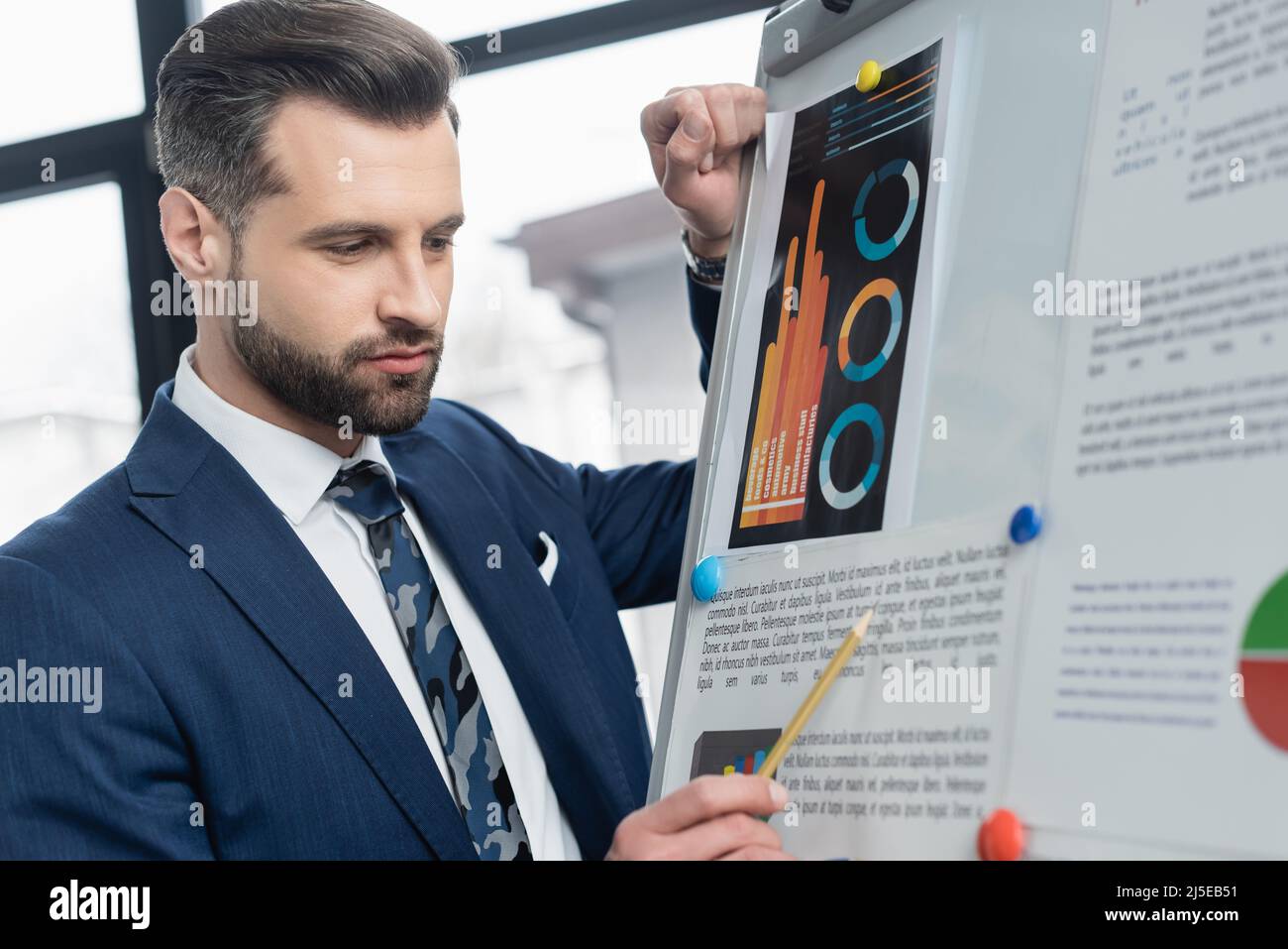 economist pointing with pencil at graphs on flip chart in office Stock ...