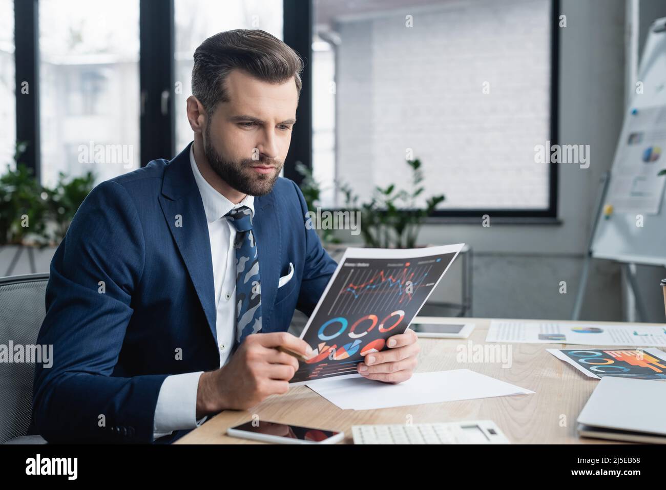 serious economist looking at infographics while working in office Stock ...