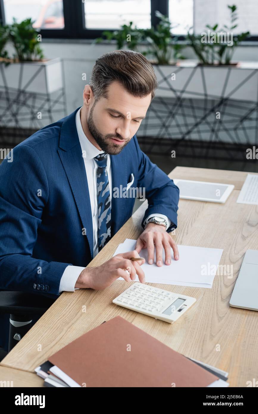 accountant in suit using calculator while working in office Stock Photo ...