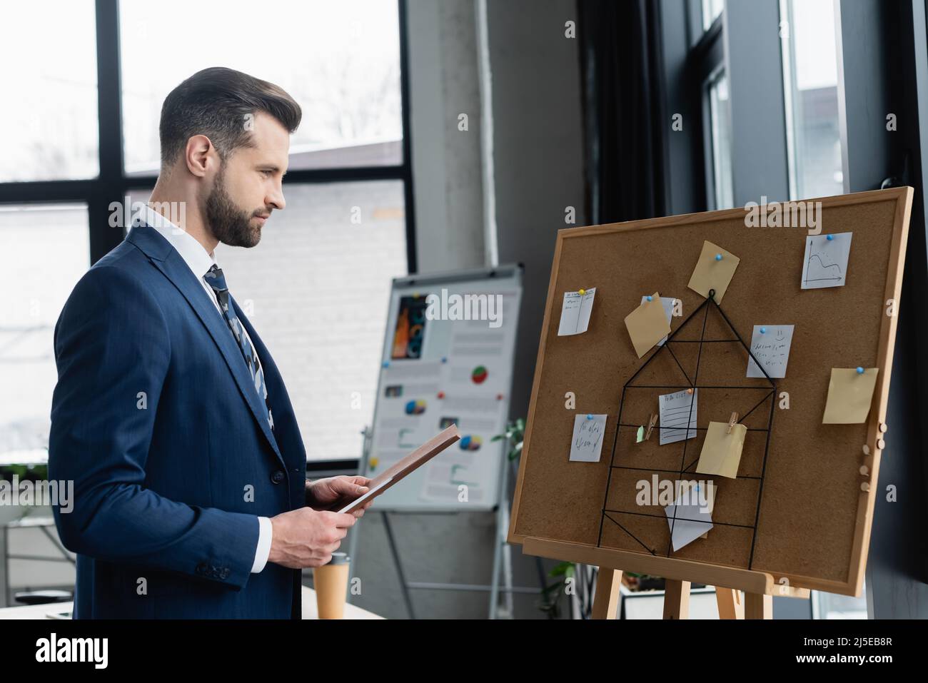 side view of economist with folder near corkboard with sticky notes and ... side view of economist with folder near corkboard with sticky notes and ...