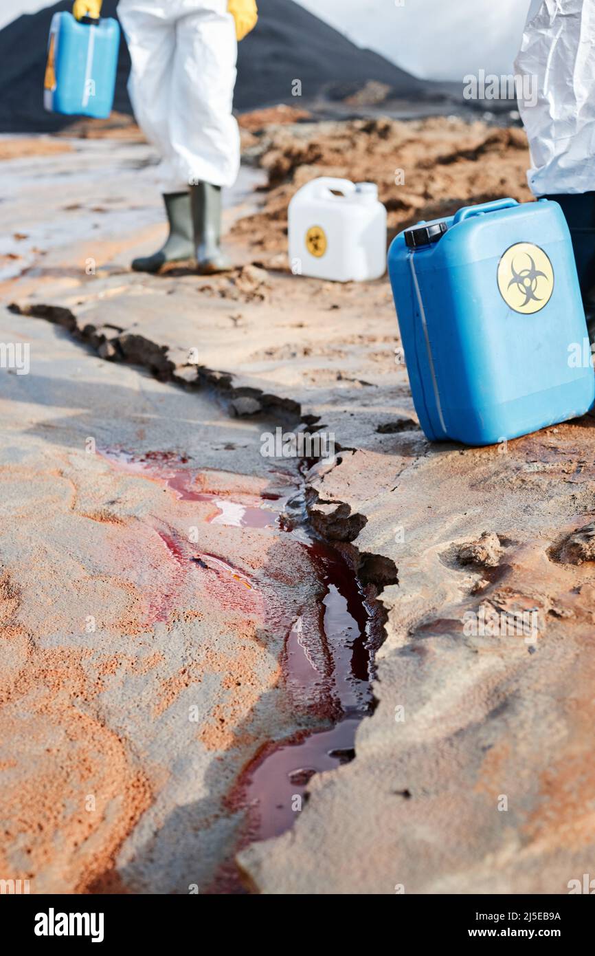 Plastic containers with toxic signs placed on polluted land near dry ...