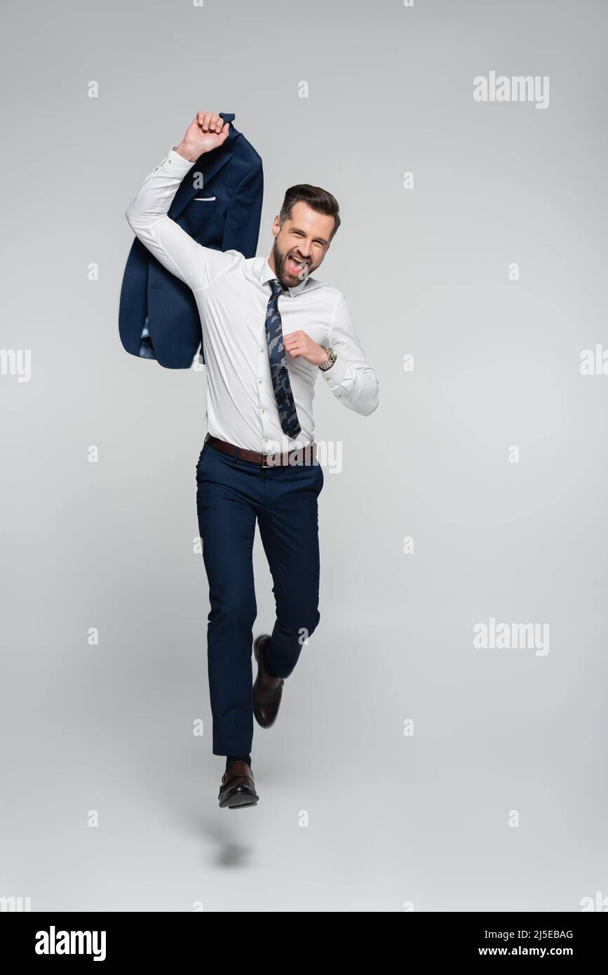 full length of overjoyed businessman running and shouting on grey Stock ...