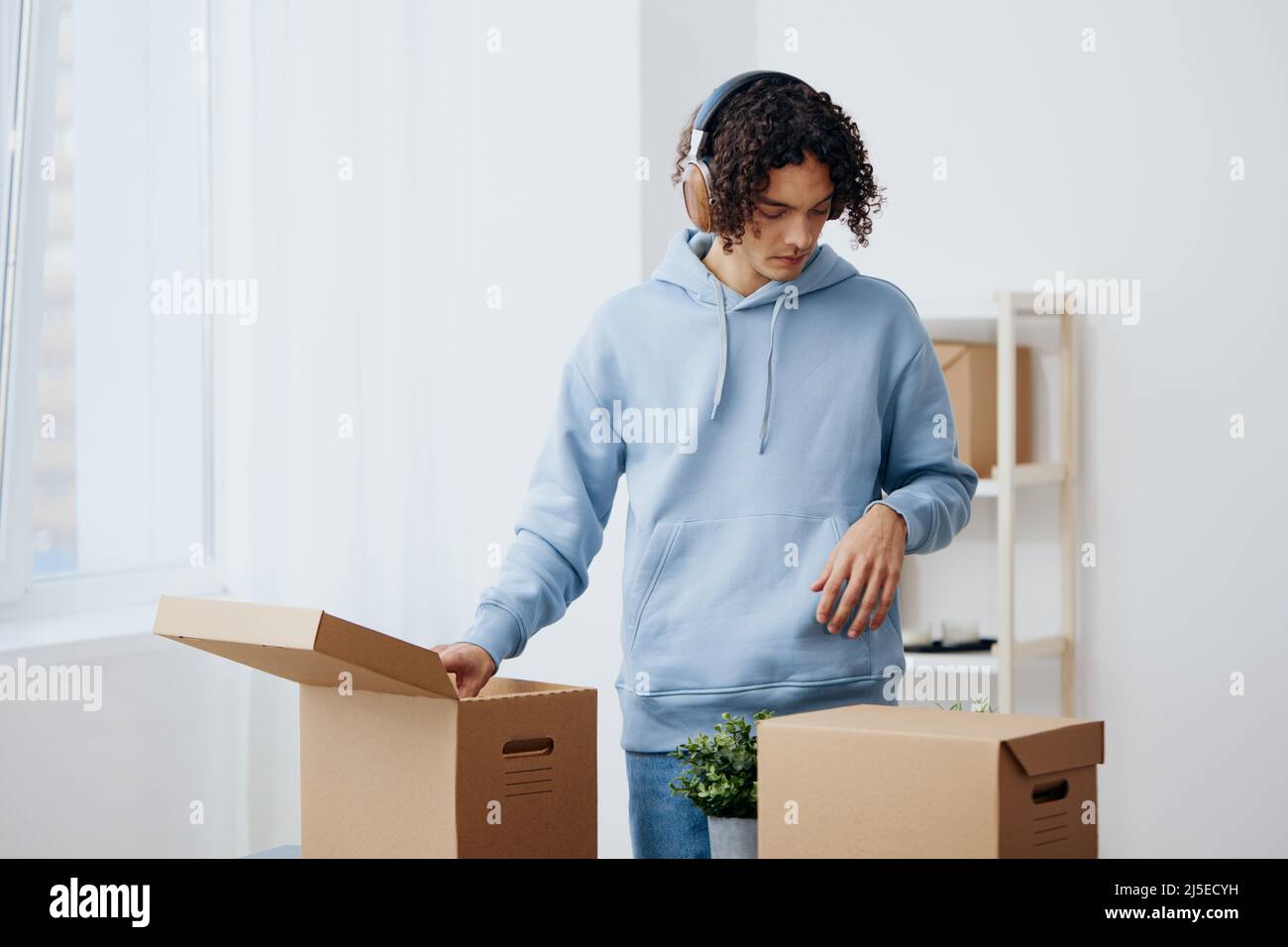 guy with curly hair unpacking things from boxes in the room sorting ...
