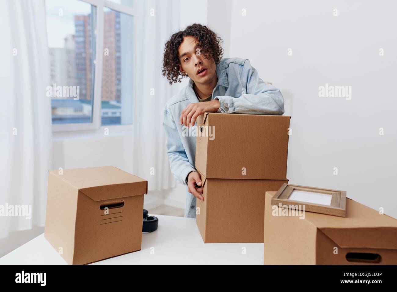 guy with curly hair unpacking with box in hand sorting things out Stock ...